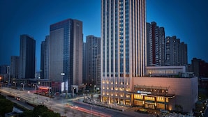 Um hotel alto com um letreiro chamativo 'WYNDHAM', rodeado por outros edifícios altos, indicando uma área urbana densa.