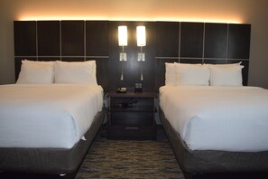Quarto de hotel com duas camas, uma mesa de cabeceira, um telefone e um candeeiro fixado na parede.