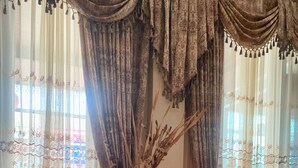 Um quarto com um banco de madeira, uma mesinha com abajur e um porta-revistas.