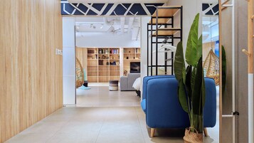 Uma sala de estar moderna com um sofá azul, uma estante de madeira e uma cadeira suspensa.