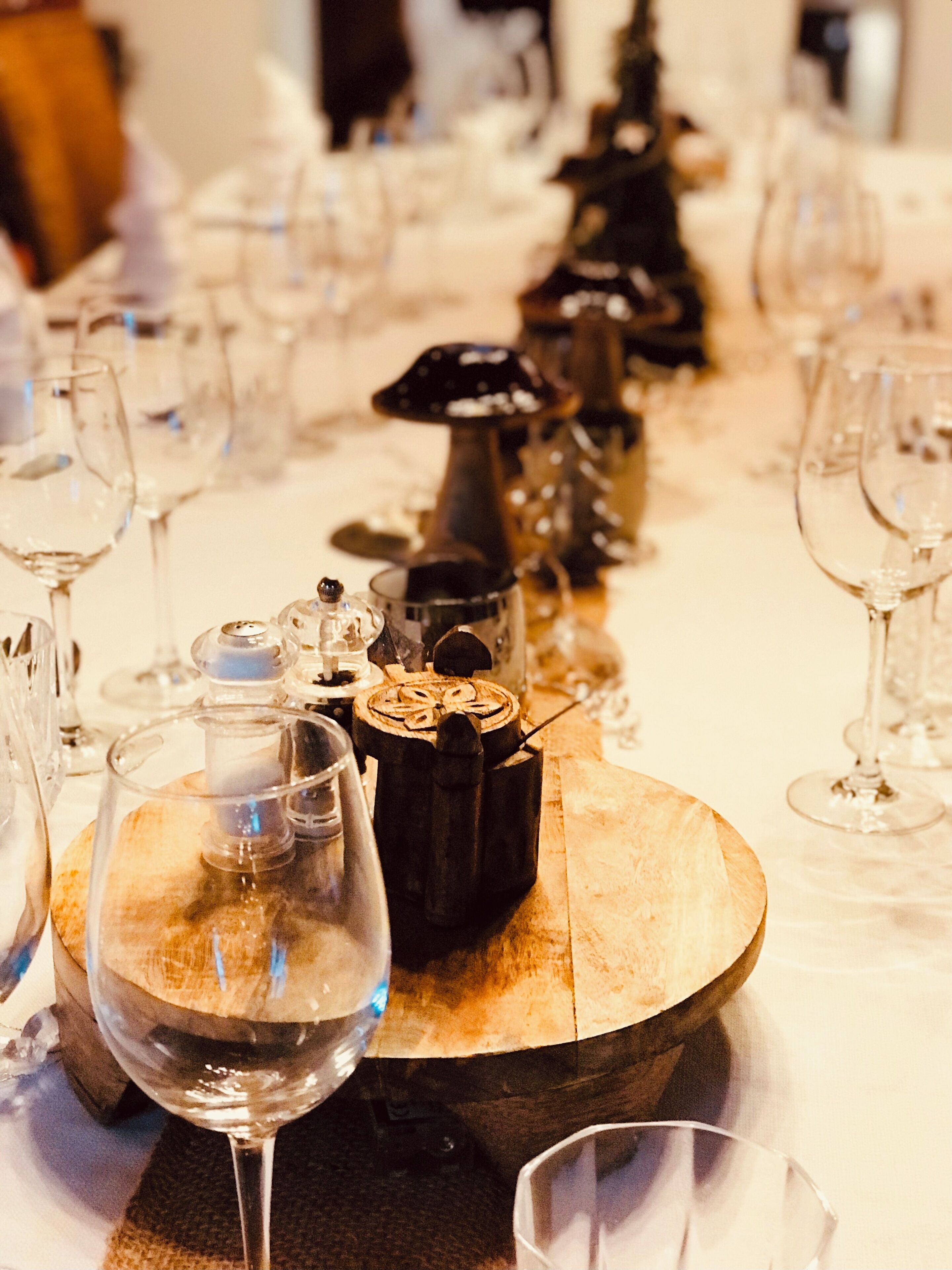 Uma mesa comprida com copos de vinho e um arranjo de madeira.