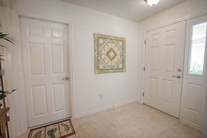 Um corredor com portas brancas, um painel de parede estampado e piso de azulejos.
