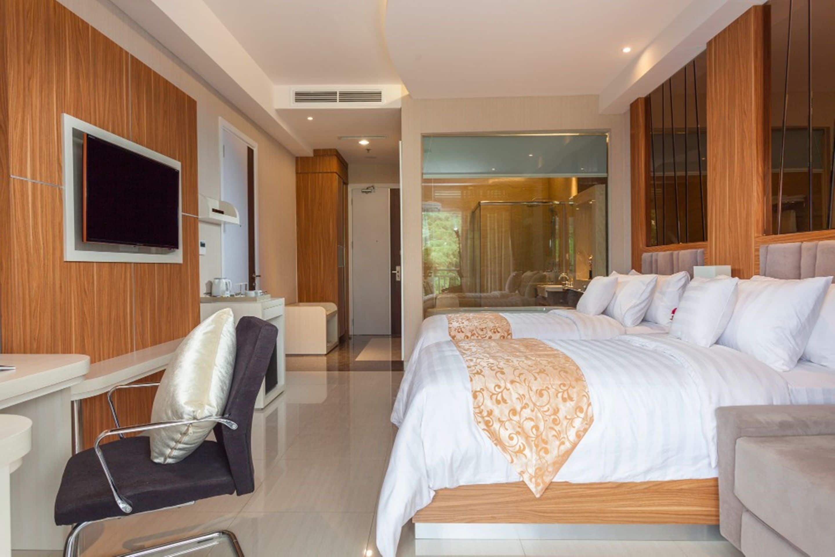 Quarto de hotel moderno com uma cama grande, uma escrivaninha, uma cadeira e uma televisão.