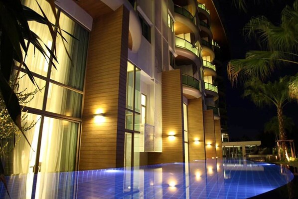 Um hotel moderno com piscina, grandes janelas e varandas.