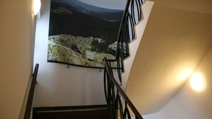 Uma escadaria com corrimão preto e um grande quadro de paisagem na parede.