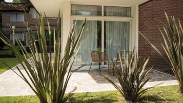 Uma casa moderna com um pátio, duas cadeiras e plantas grandes.