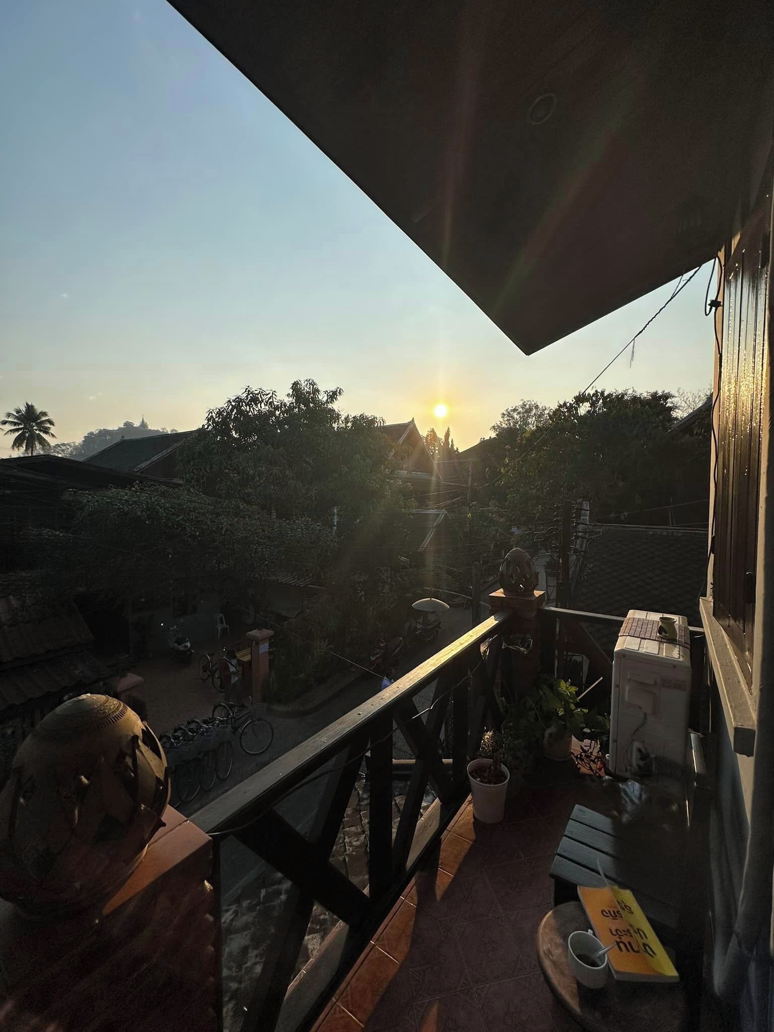 Varanda com vista para o pôr do sol, uma bicicleta e alguns vasos de plantas.