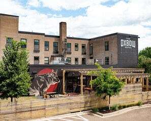 Hotel com fachada de tijolos, área de estar ao ar livre e um grande mural de um touro.
