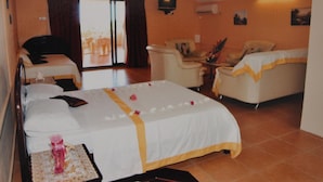 Quarto de hotel com uma cama, duas cadeiras, uma mesa pequena e uma televisão.