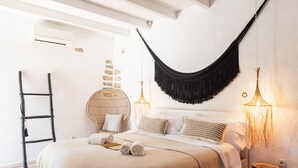 Uma cama com rede, uma escada e uma parede de pedras.