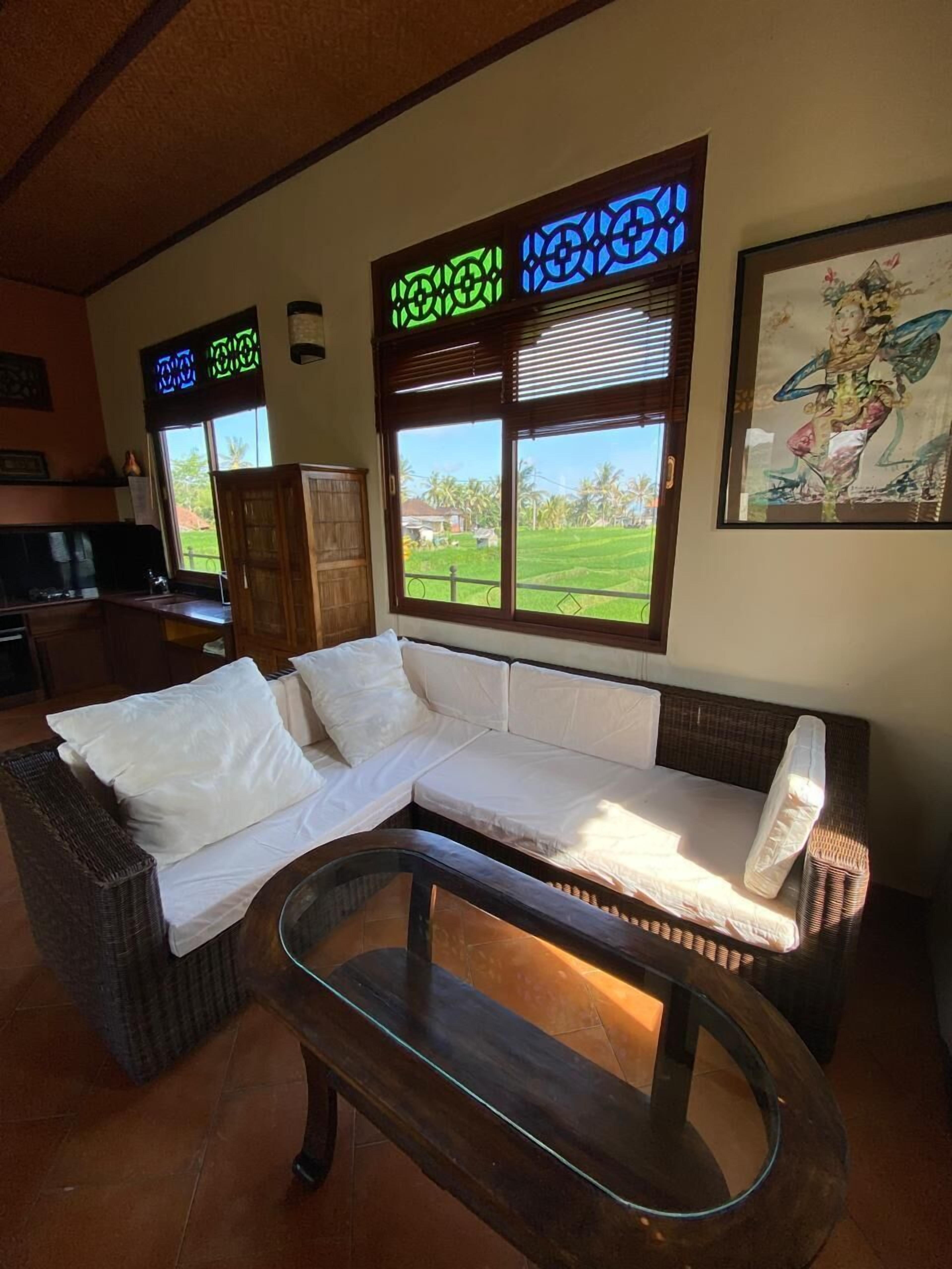 Uma sala de estar com sofá, mesa de centro de vidro e um quadro na parede.