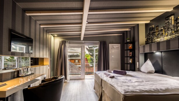 Quarto de hotel moderno com cama, escrivaninha, televisão e vista para a cidade.