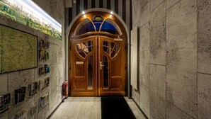 Um corredor com uma porta dupla de madeira, um extintor de incêndio e um mapa na parede.