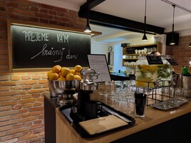 Uma área de bar com um menu em lousa, uma cesta de frutas e uma máquina de café.