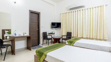 Quarto de hotel com duas camas, uma escrivaninha, uma cadeira, uma televisão e um aparelho de ar condicionado.
