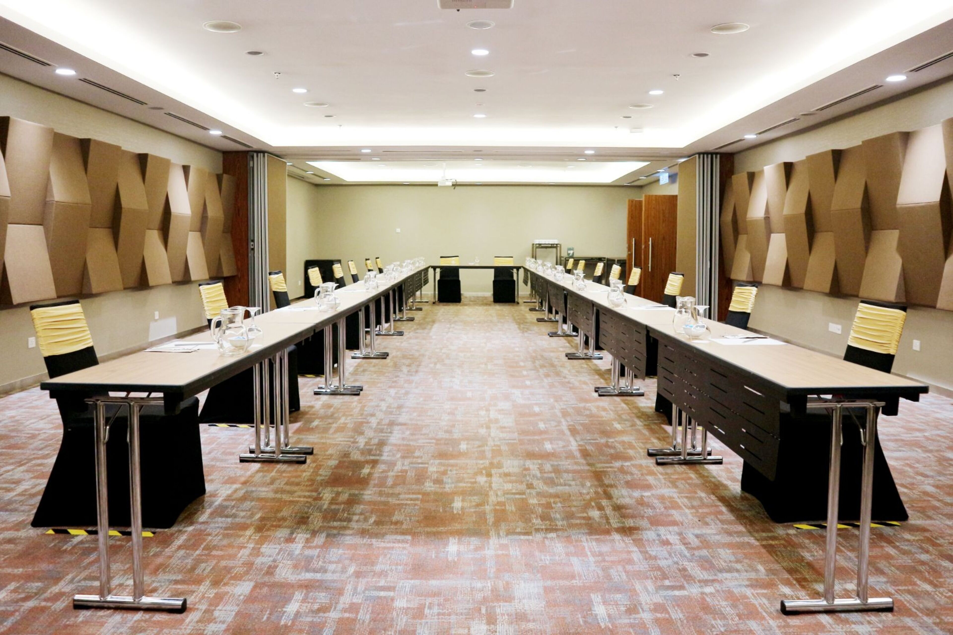 Uma sala de conferências com uma mesa comprida, cadeiras e esquema de cores neutras.