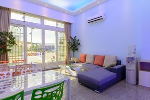 Uma sala de estar moderna com uma mesa de jantar de vidro, um sofá e um dispensador de água.