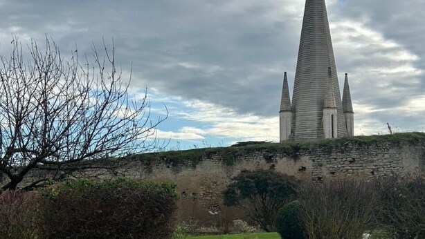 Igreja com uma torre alta e um muro de pedra ao fundo.