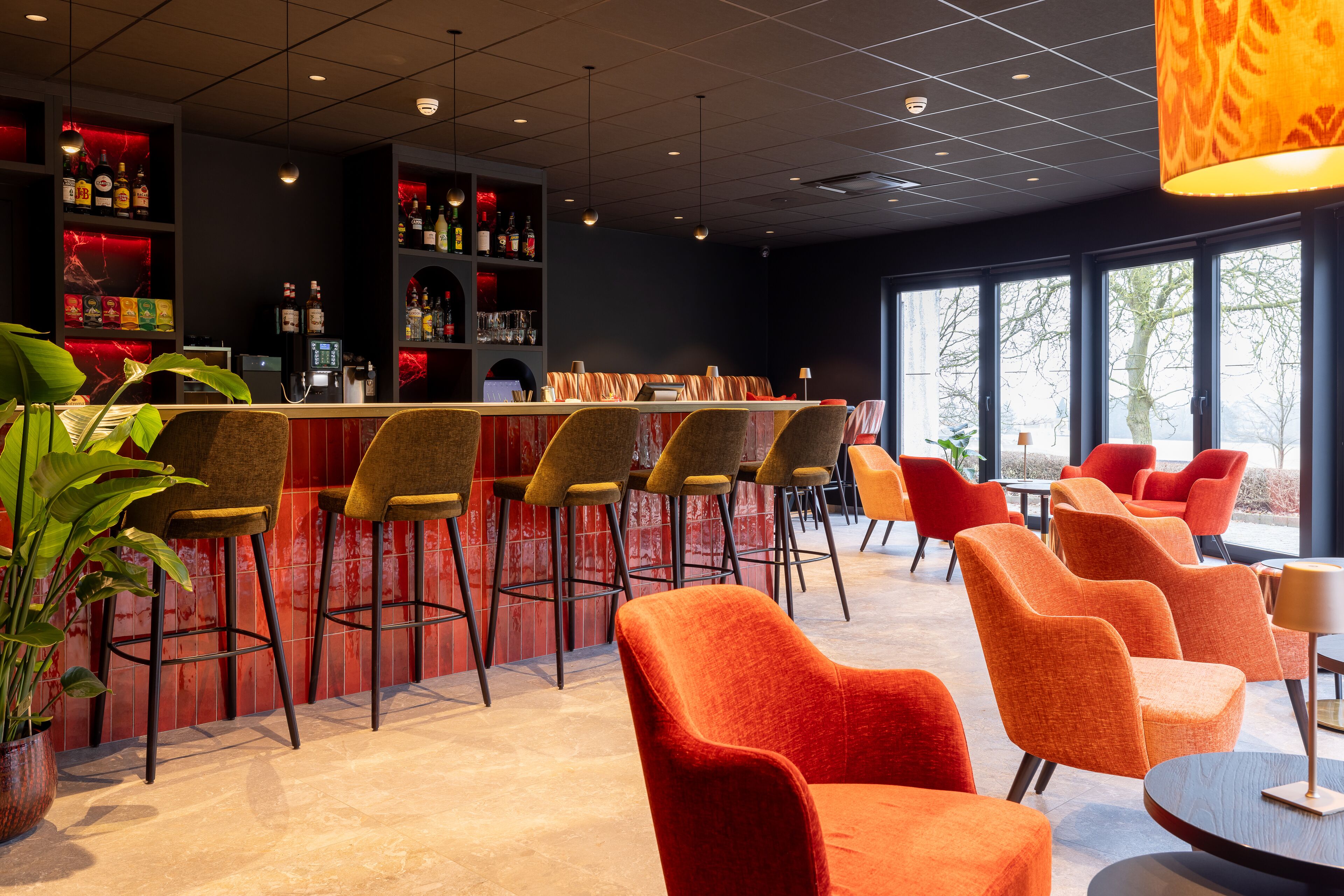 Uma área de bar com diversas opções de assento, incluindo banquetas e cadeiras, e um balcão com vários tipos de garrafas e copos.