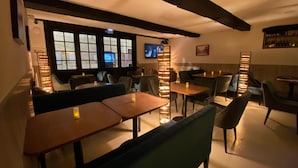 Um restaurante com cabines e mesas, uma tela de televisão e um espaço de bar.
