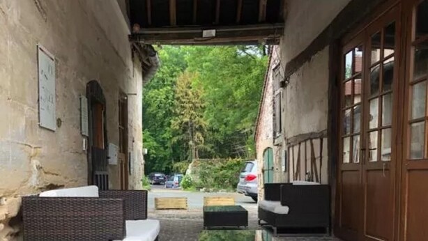 Uma área de estar externa com móveis de vime e piso de tijolos.