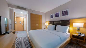 Quarto de hotel com uma cama grande, mesas de cabeceira com abajures, uma televisão e um guarda-roupa de madeira.