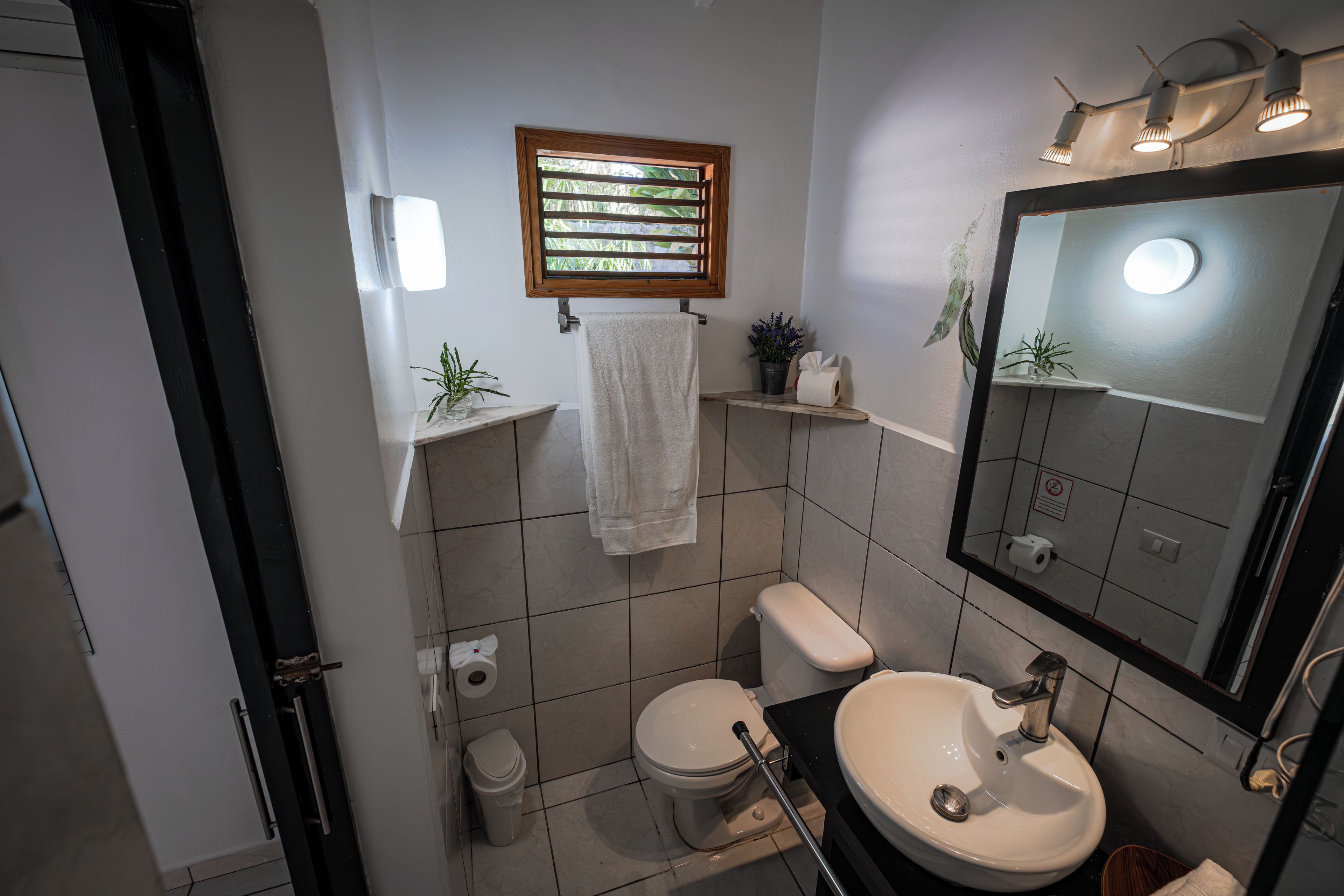 Casa de banho compacta com sanita, bidé, lavatório e espelho.