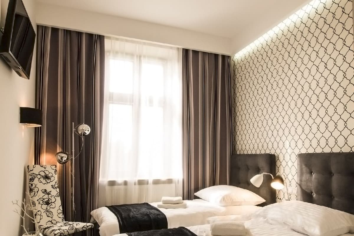 Quarto de hotel com duas camas, televisão, escrivaninha e uma cadeira.