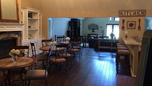 Uma área de refeições com lareira, piso de madeira e um candelabro. Há uma cozinha com uma placa identificada como