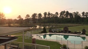 Piscina com deck ao redor, área de churrasco e vista para um lago e árvores.