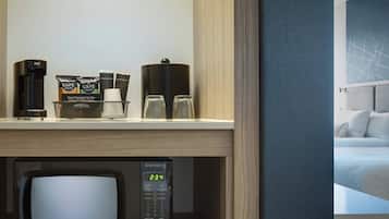 Minibar de hotel com micro-ondas Daewoo, cafeteira e dispensador de café.