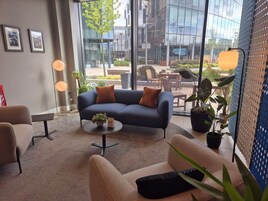 Espaço de escritório moderno com sofá, cadeiras, mesa de centro e plantas em vasos.
