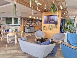 Uma área de estar moderna com assentos, um bar e uma tela de televisão.