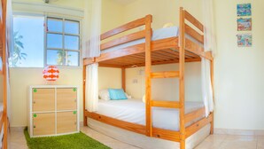 Quarto com beliche, tapete verde, armário pequeno e janela com cortinas.