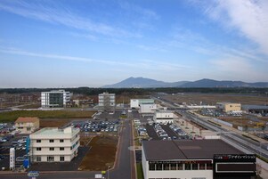 Uma área comercial com estacionamentos, edifícios e uma montanha ao fundo.