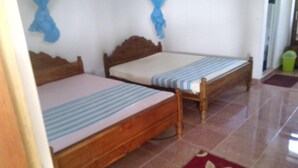 Quarto com duas camas de madeira, cada uma com colcha listrada.