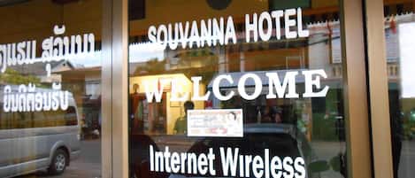 Entrada de hotel com um letreiro de 'Welcome' e aviso de 'Internet Wireless'.