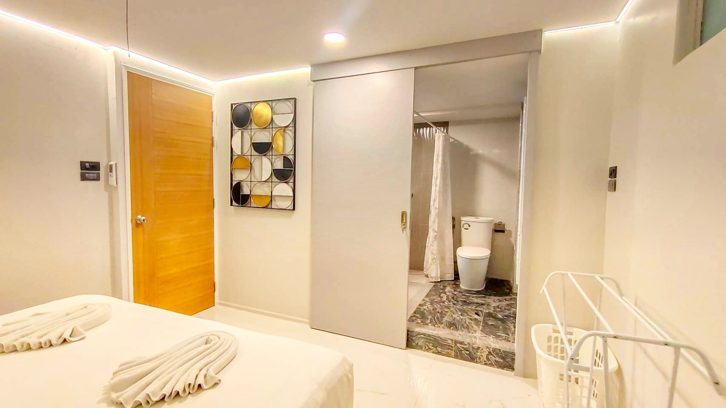 Quarto de hotel com cama, banheiro visível através de uma porta deslizante e um porta-toalhas.