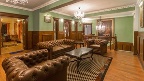 Um quarto espaçoso com um amplo sofá de couro marrom, uma poltrona combinando, uma mesa de centro de madeira e um tapete estampado.