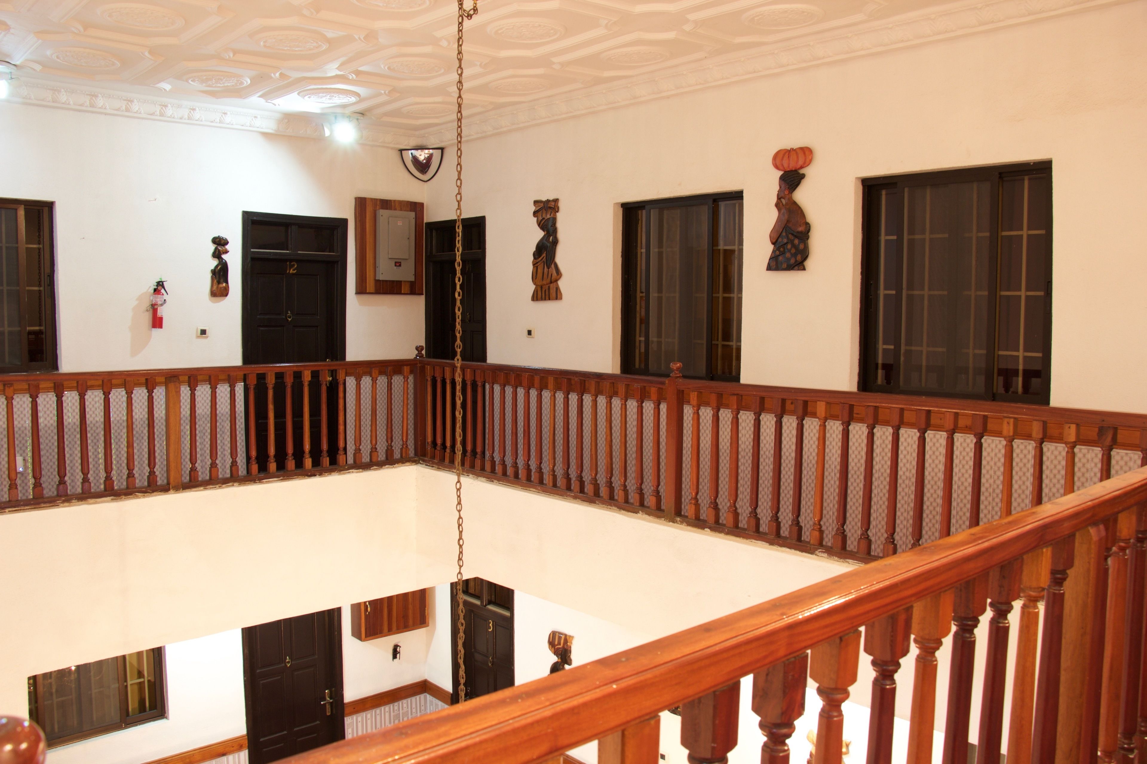 Interior espaçoso com teto alto, várias portas e escadaria de madeira.