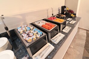 Um buffet com diversos alimentos e utensílios.