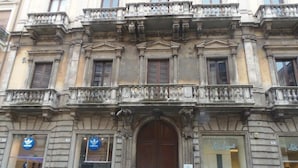 Um edifício histórico com uma grande entrada central, várias janelas e varandas.