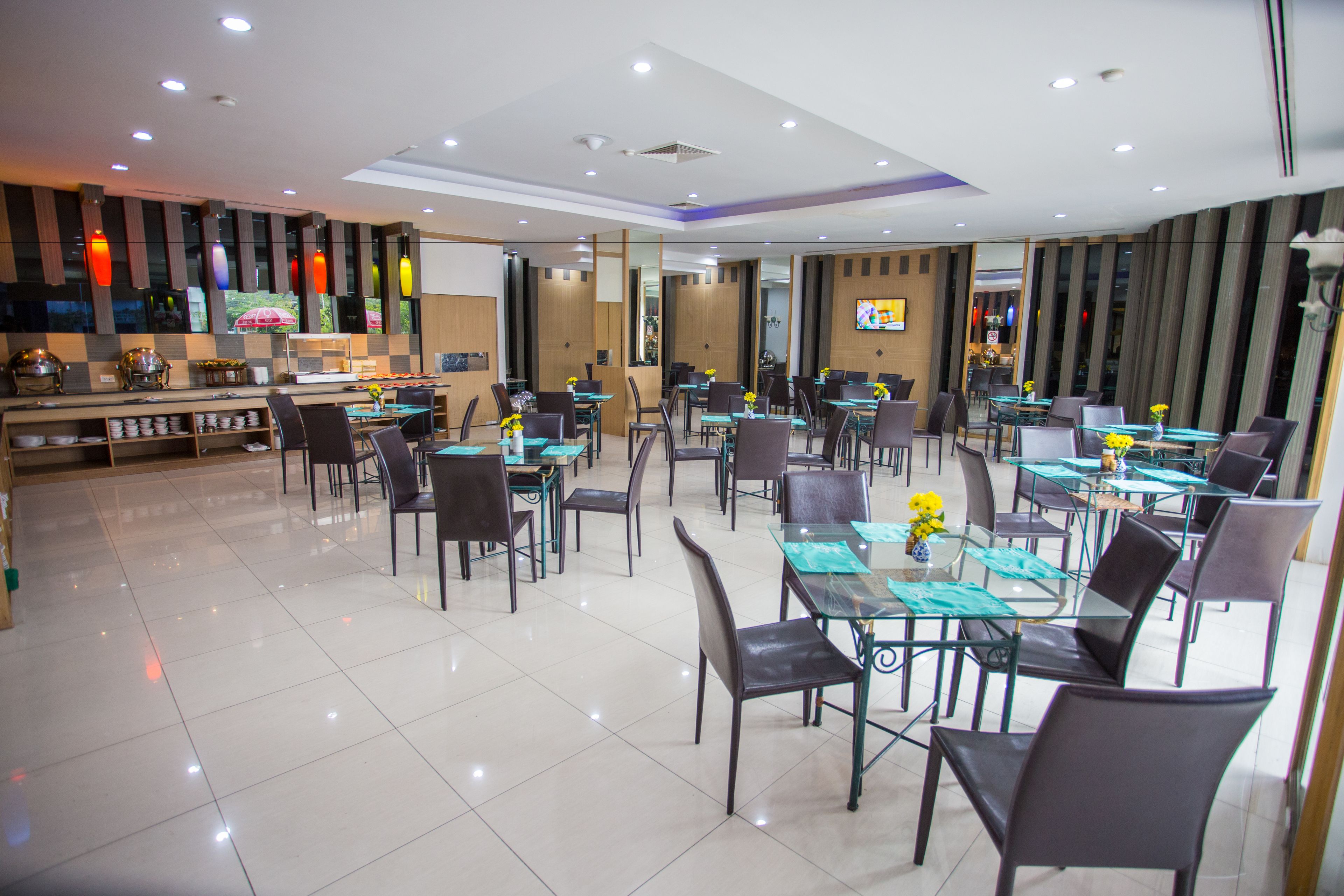 Um restaurante moderno com piso de azulejos e mesas e cadeiras de vidro.