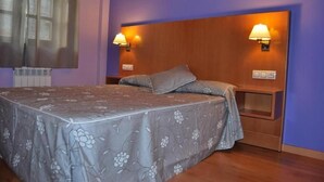 Quarto com uma cama, duas luminárias na parede e uma mesa de cabeceira.
