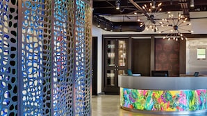 Uma área de recepção moderna com um display digital colorido, um divisório de metal perfurado e um design de teto contemporâneo.