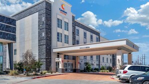Um hotel Comfort Suites com design moderno, apresentando fachada de pedra e entrada coberta.