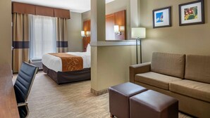 Quarto de hotel com cama, sofá, escrivaninha e cadeira.