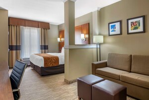 Quarto de hotel com cama, sofá, escrivaninha e cadeira.