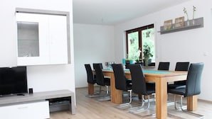 Uma área de jantar moderna com mesa de madeira e cadeiras pretas, uma televisão de tela plana e um armário embutido.