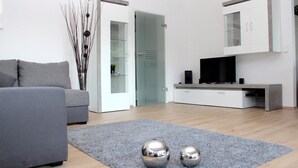 Uma sala de estar moderna com um sofá cinza, uma televisão de tela plana e um aparador com portas de vidro.